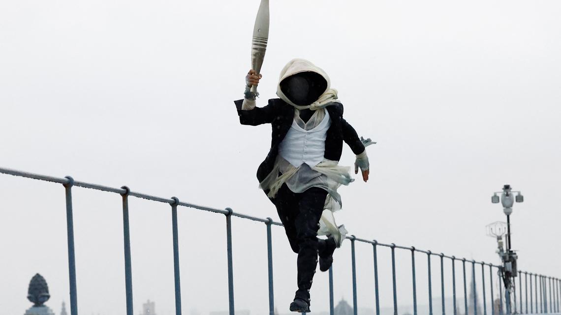 Who is the hooded figure with the Olympic torch? | 9news.com